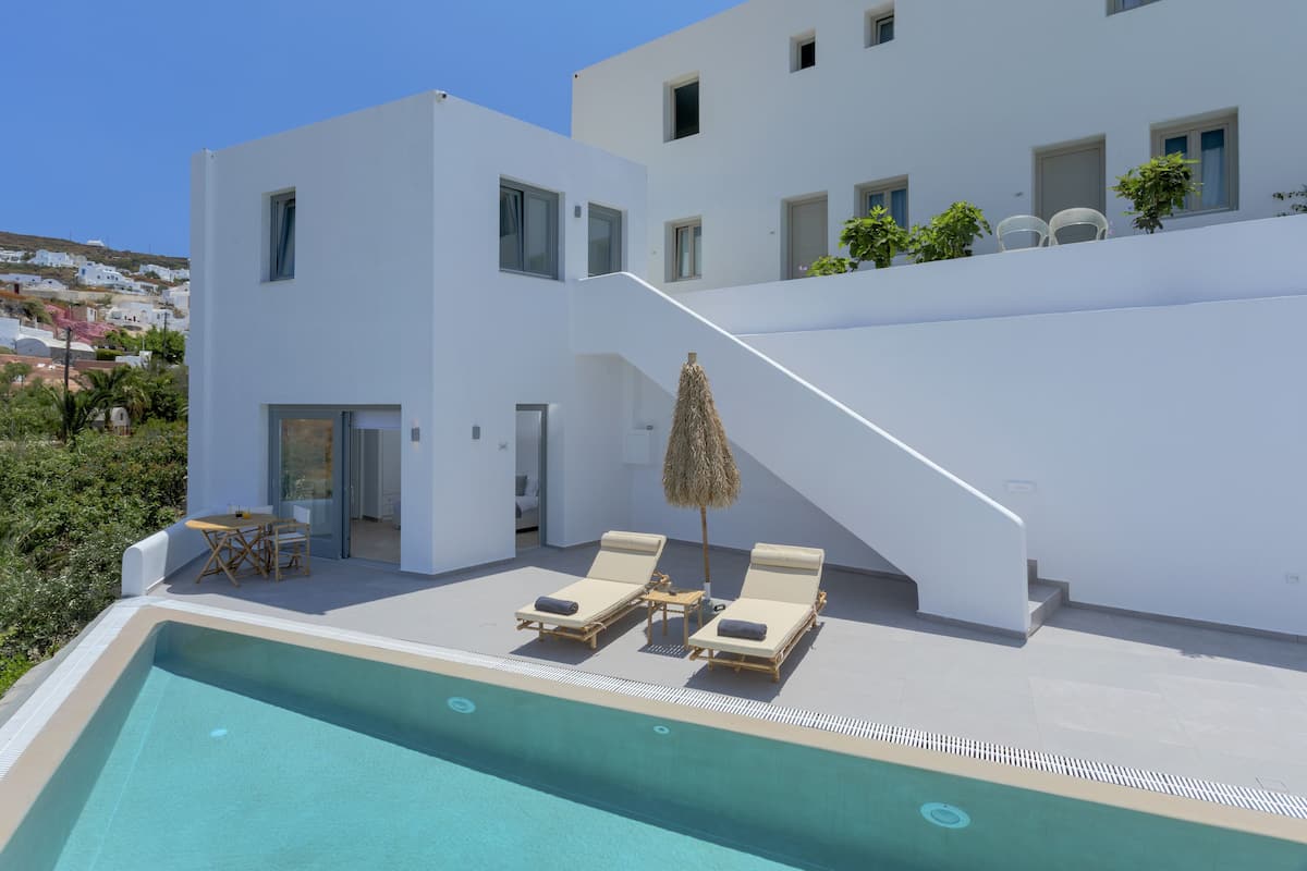 Um edifício moderno e branco com piscina, cadeiras de descanso e uma escadaria.