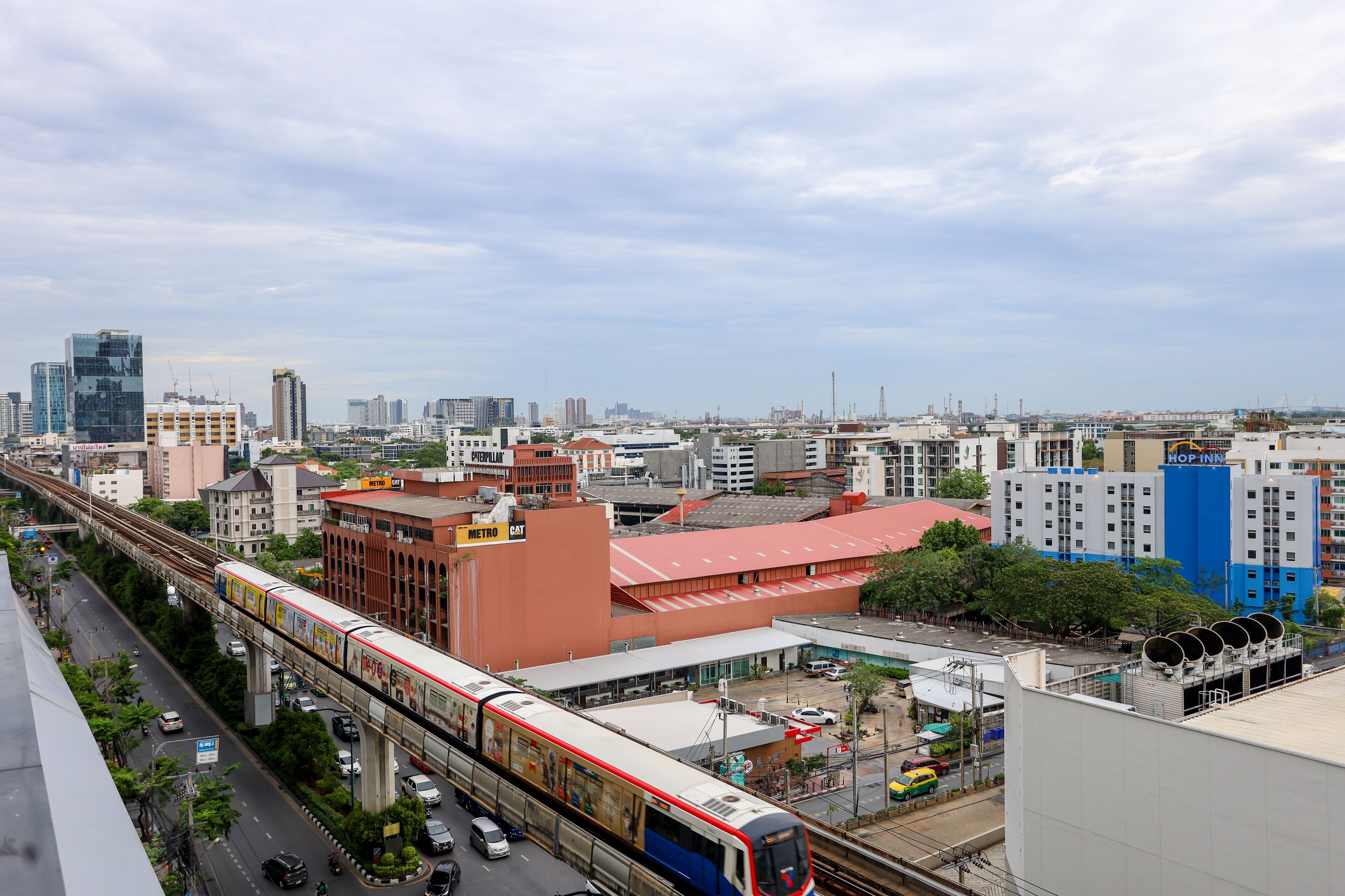 Um trem passando por uma paisagem urbana com edifícios modernos e uma linha de metrô.