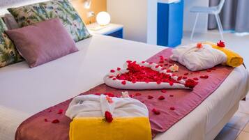 Quarto de hotel com cama, escrivaninha, cadeira e janela com cortinas.