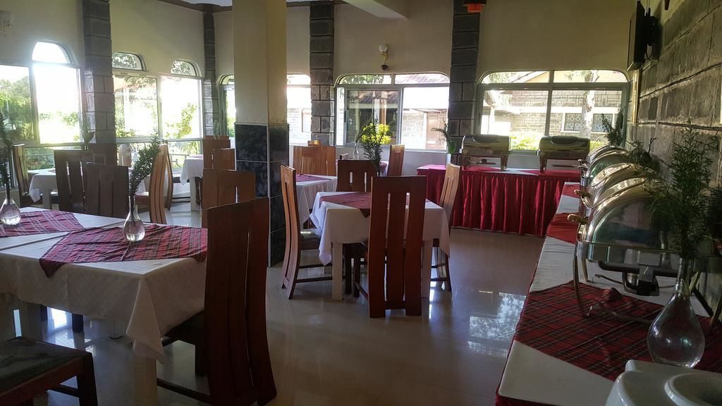 Restaurante com mesas montadas para refeições, cadeiras e uma área de buffet.