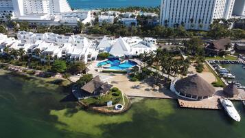 Vista aérea de um resort com piscina central, vários edifícios e um porto de iates.