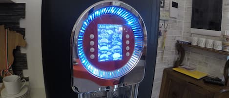 Uma máquina de café com menu digital, uma pia e um armário de madeira ao fundo.