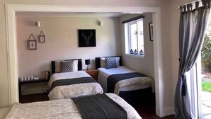 Quarto com duas camas, uma janela com cortinas, mesa de cabeceira e um quadro pendurado na parede.