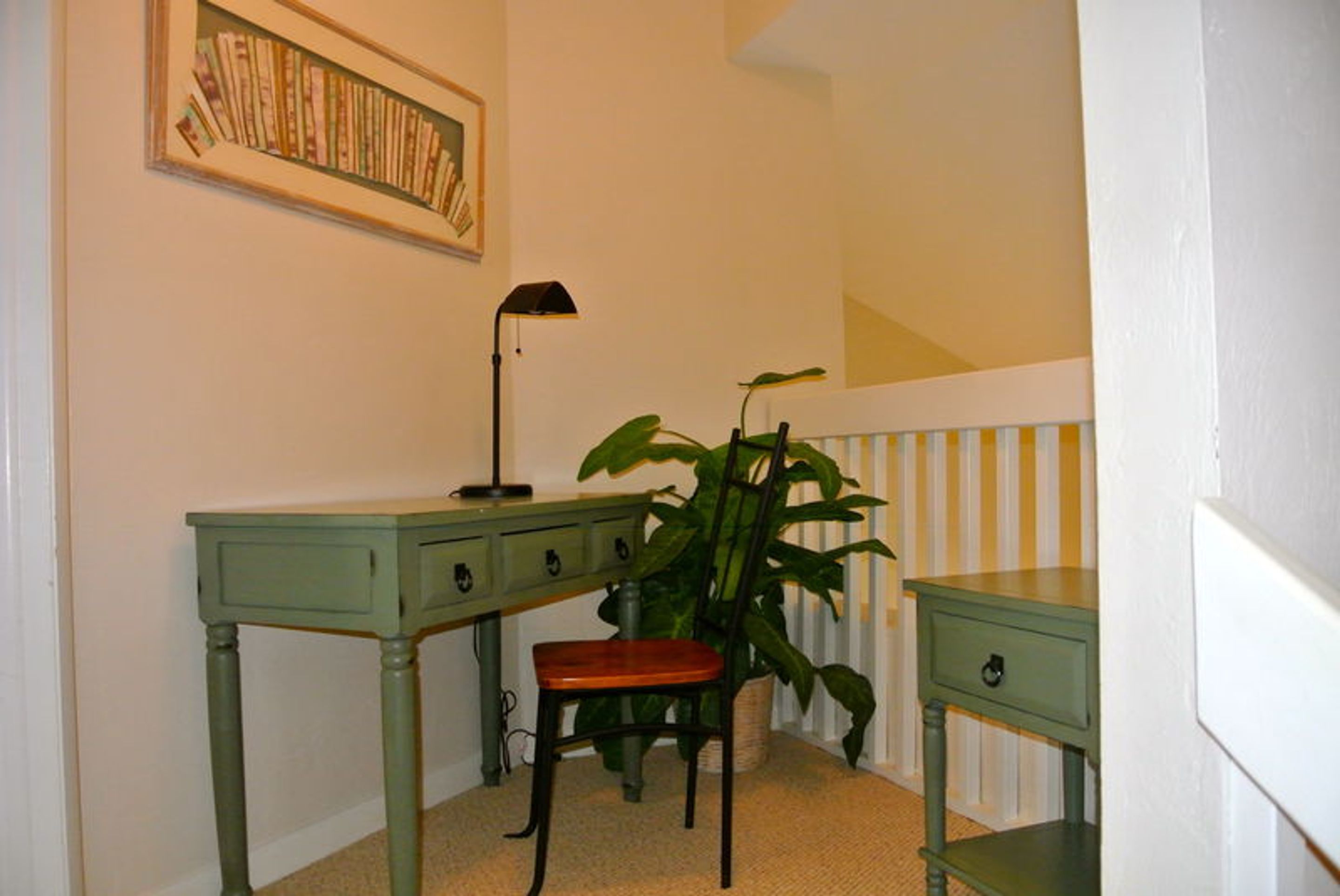 Quarto de canto com escrivaninha, cadeira, abajur e planta em vaso.