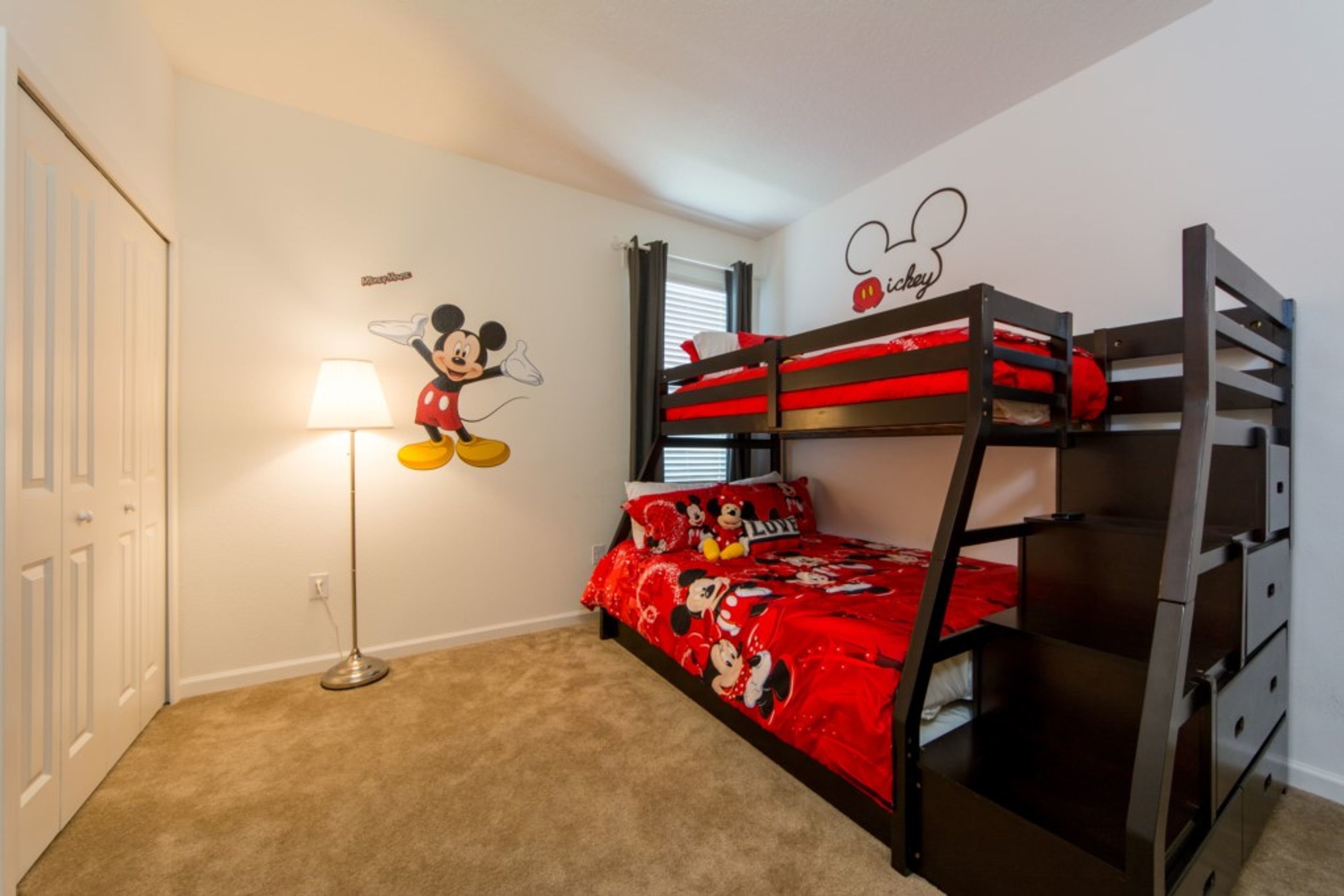 Quarto de criança com beliche, adesivo de parede do Mickey Mouse e luminária.