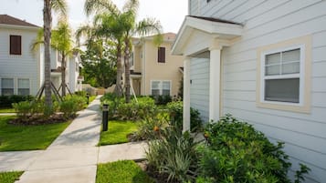 Rua residencial com casas, calçada e vegetação.