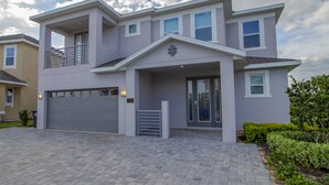 Uma casa moderna de dois andares com garagem, varanda e um jardim bem cuidado.