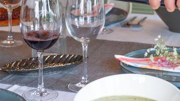 Uma mesa de jantar com copos de vinho, uma tigela de sopa e uma garrafa sendo servida em um dos copos.