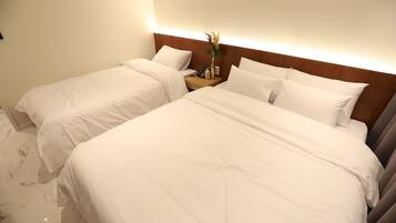 Quarto de hotel com duas camas de solteiro, cabeceira de madeira, mesa de cabeceira com um vaso e piso de mármore.