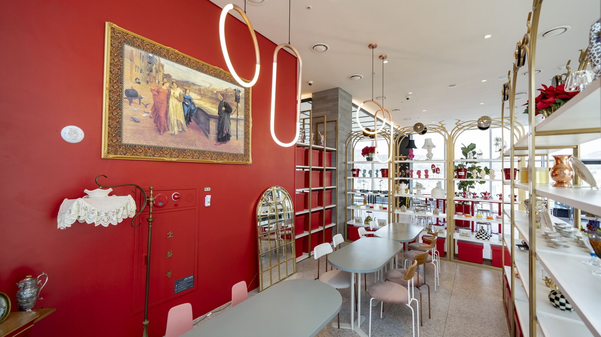 Interior de um hotel boutique com uma parede vermelha, uma grande pintura emoldurada e diversos objetos decorativos em prateleiras.