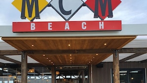 Um edifício com tema praiano e um letreiro grande com a inscrição 'MCM BEACH'.