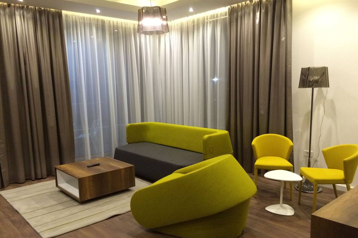 Uma sala de estar moderna com um sofá, duas poltronas, uma mesa de centro e um abajur.