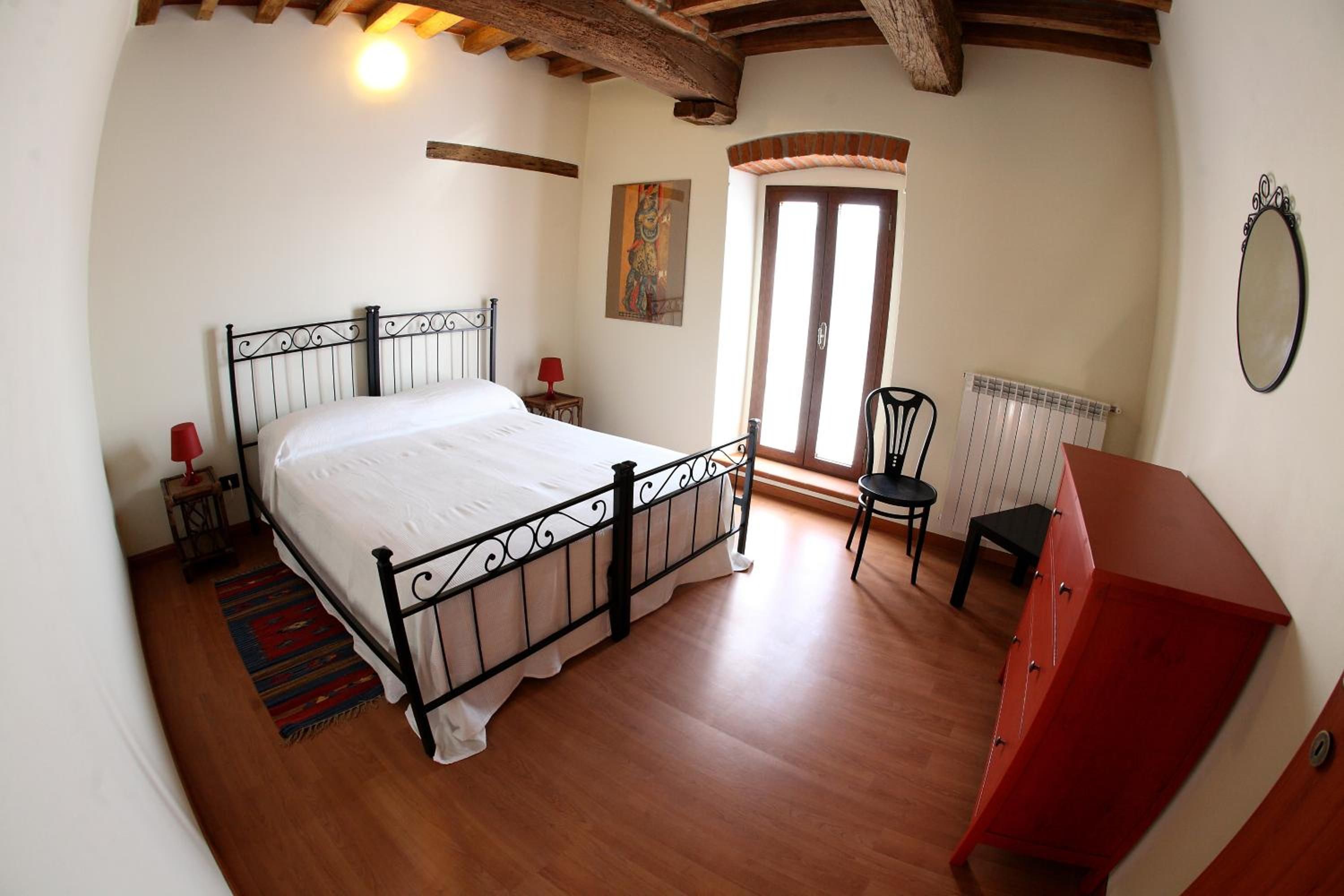 Quarto com cama, cadeira, penteadeira, radiador e porta com janela.