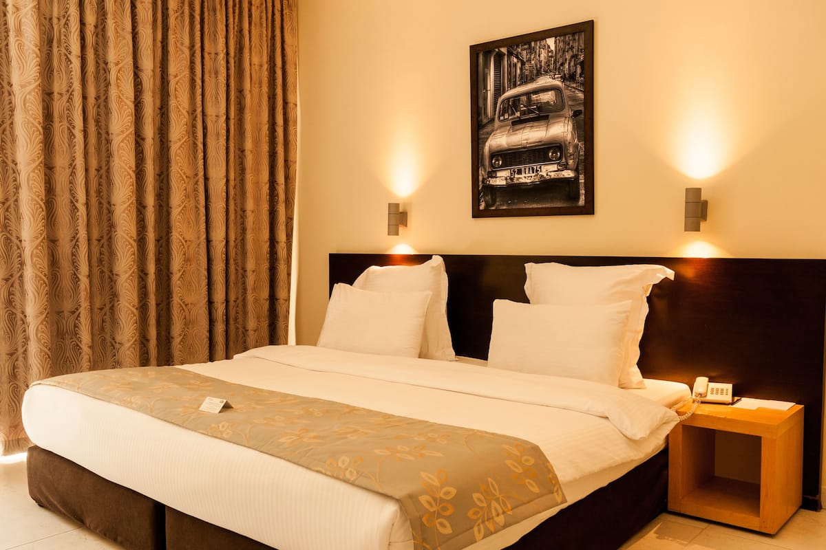 Quarto de hotel com cama grande, duas mesas de cabeceira, uma cabeceira e um quadro pendurado na parede.