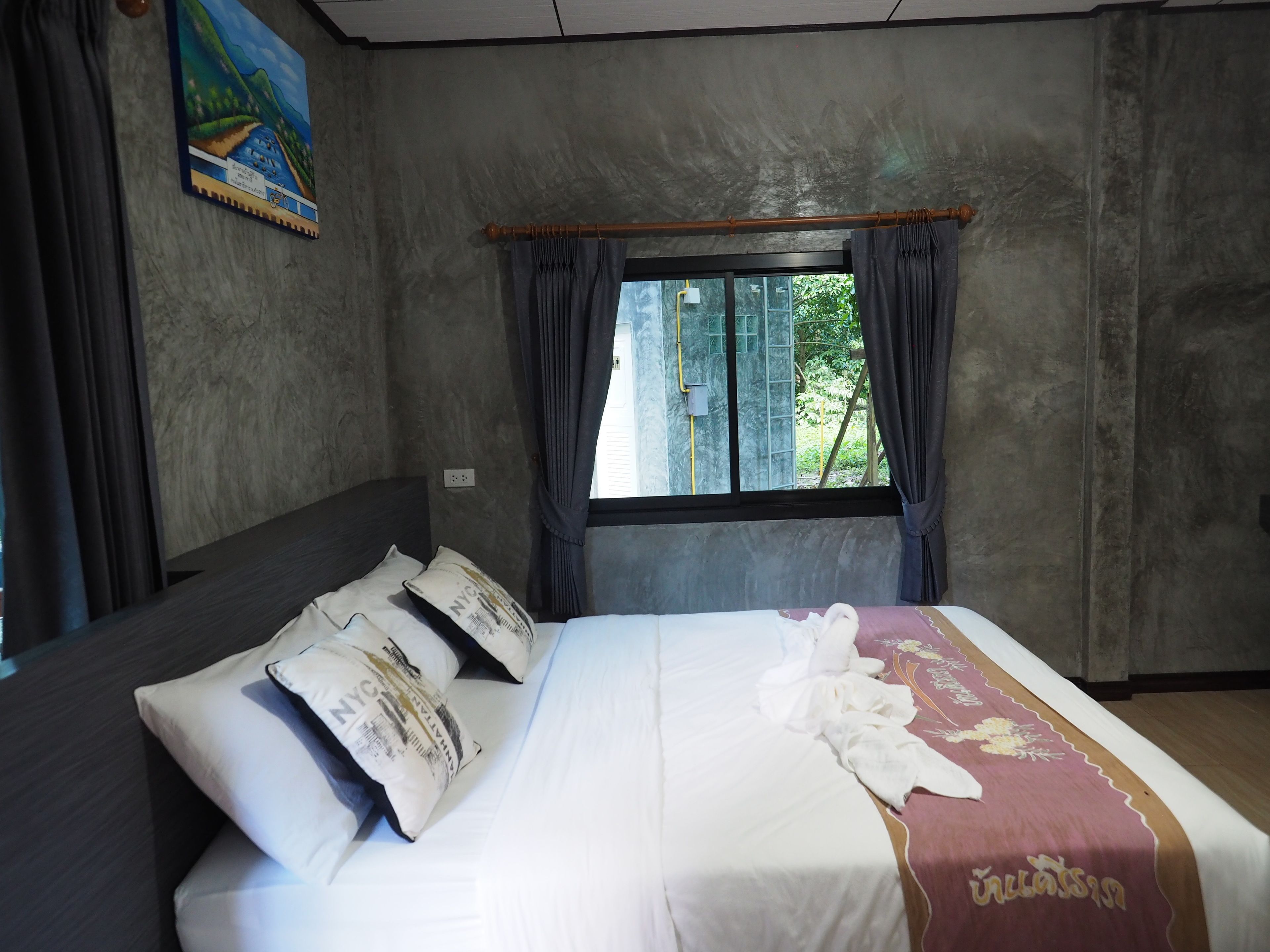 Quarto com cama, janela e um quadro na parede.