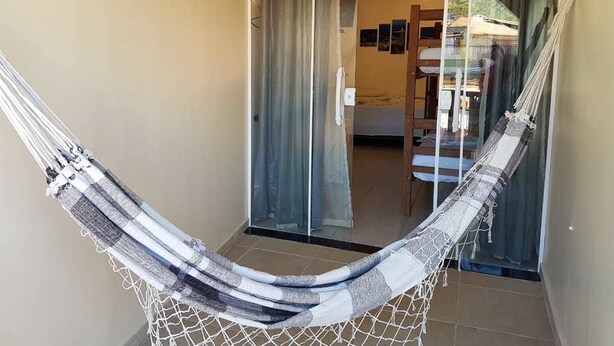 Uma rede em um quarto com uma porta de correr de vidro que dá para uma varanda.