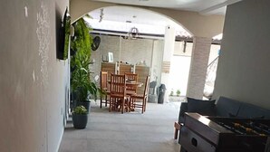 Um corredor com uma mesa de pebolim, uma área de jantar com cadeiras e uma mesa, e uma porta com um tapete de entrada da 'Hope Pousada'.