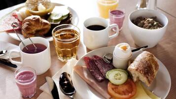 Disposição para o café da manhã com pratos de comida, bebidas e utensílios sobre uma mesa.