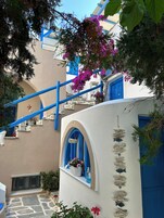 Um edifício tradicional branco com detalhes em azul, uma escadaria de pedra e uma varanda florida.