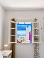 Quarto com janela, uma pequena mesa com abajur e vista para a costa.