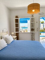 Quarto com cama, janela com vista, luminária pendente e mesa de cabeceira.