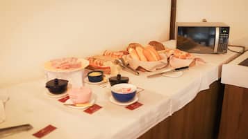 Uma mesa de buffet com diversos alimentos, incluindo pão, doces e tigelas de sopa.