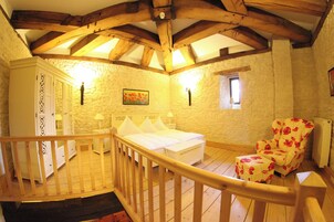 Quarto com teto de madeira, uma cama, uma cadeira e uma mesa de cabeceira.