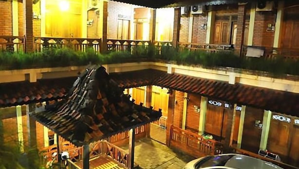 Um edifício com vários andares e arquitetura tradicional, com área de estar coberta ao ar livre e várias portas de madeira.
