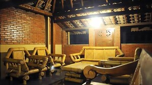 Quarto rústico com parede de tijolos, móveis de madeira e teto com vigas aparentes.