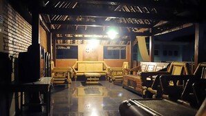 Um quarto com iluminação fraca, piso de madeira, um sofá e uma esteira.