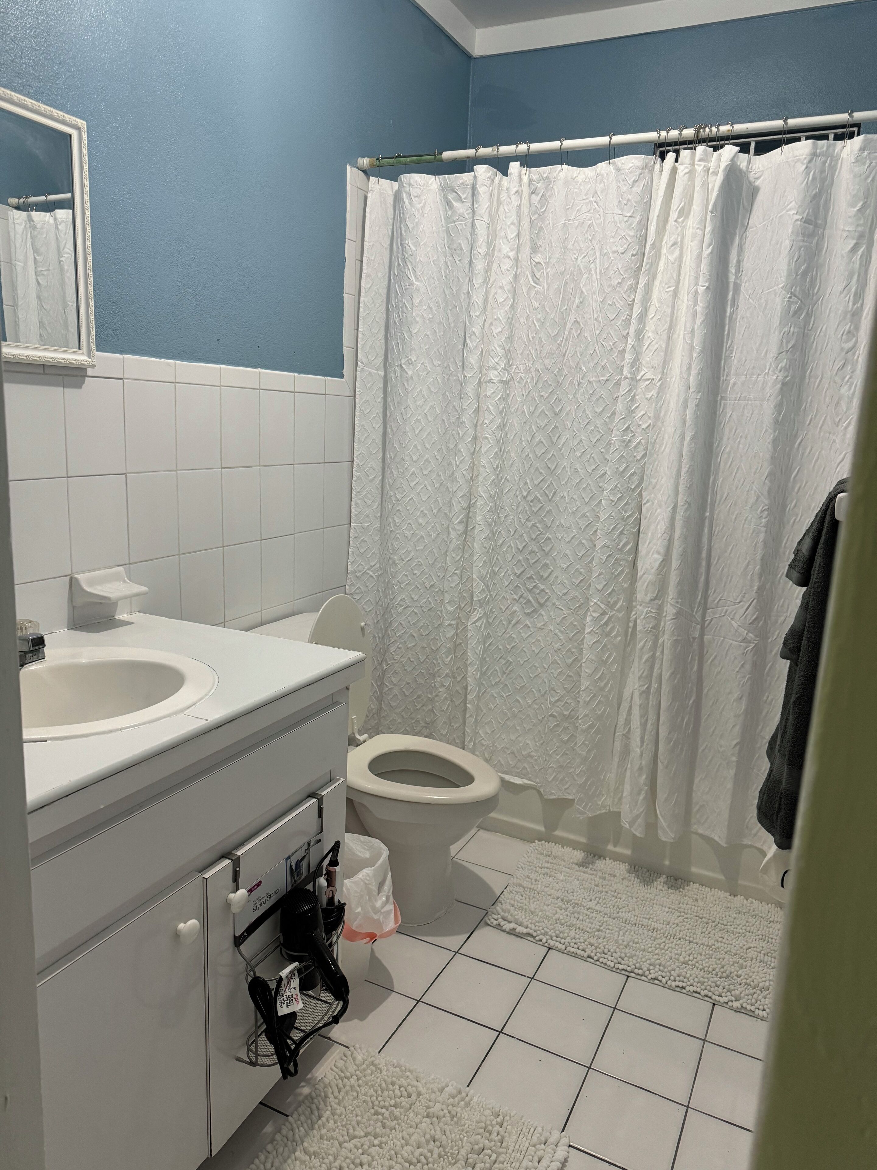 Casa de banho com lavatório branco, sanita e cortina de chuveiro.
