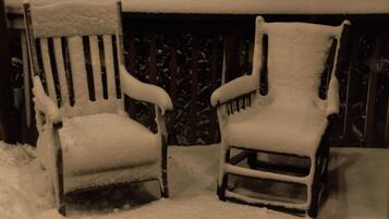 Duas cadeiras cobertas de neve em frente a uma cerca de madeira.