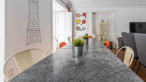 Cozinha moderna com bancada de mármore, duas plantas em vasos e um relógio de parede.