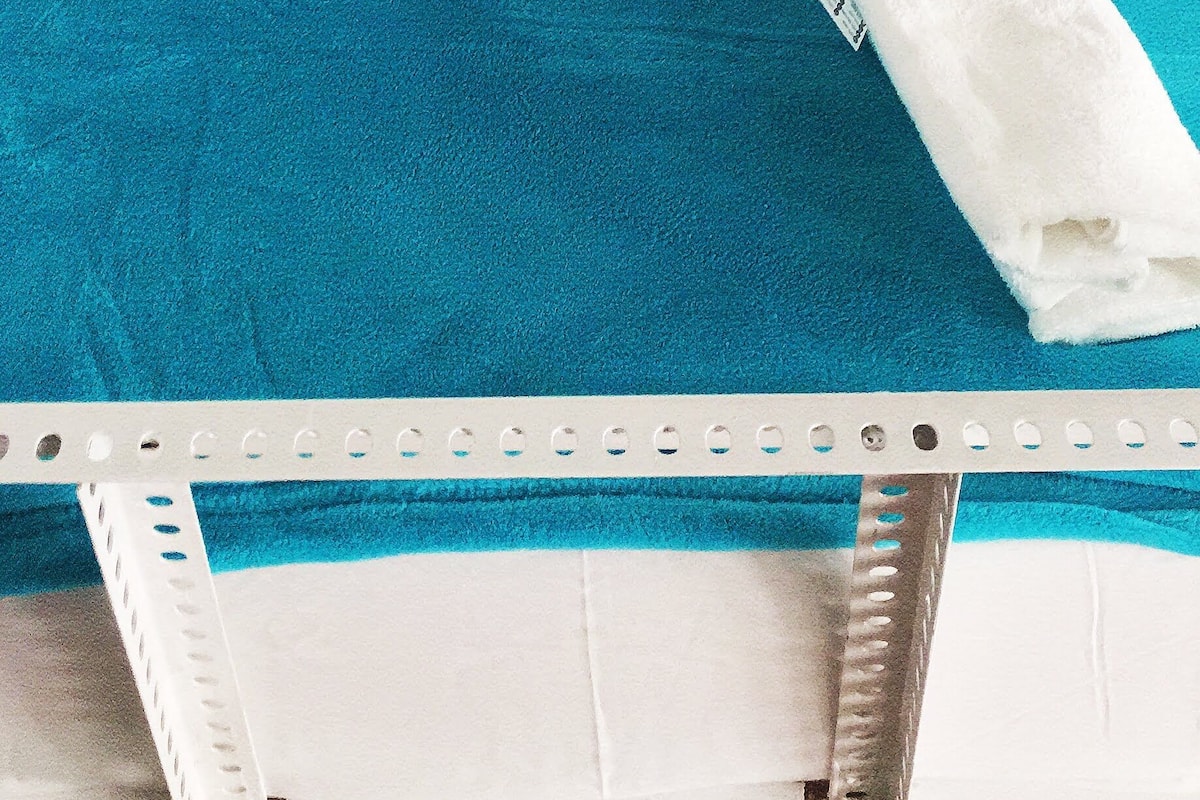 Uma cama de solteiro com colchão branco e cobertor azul.