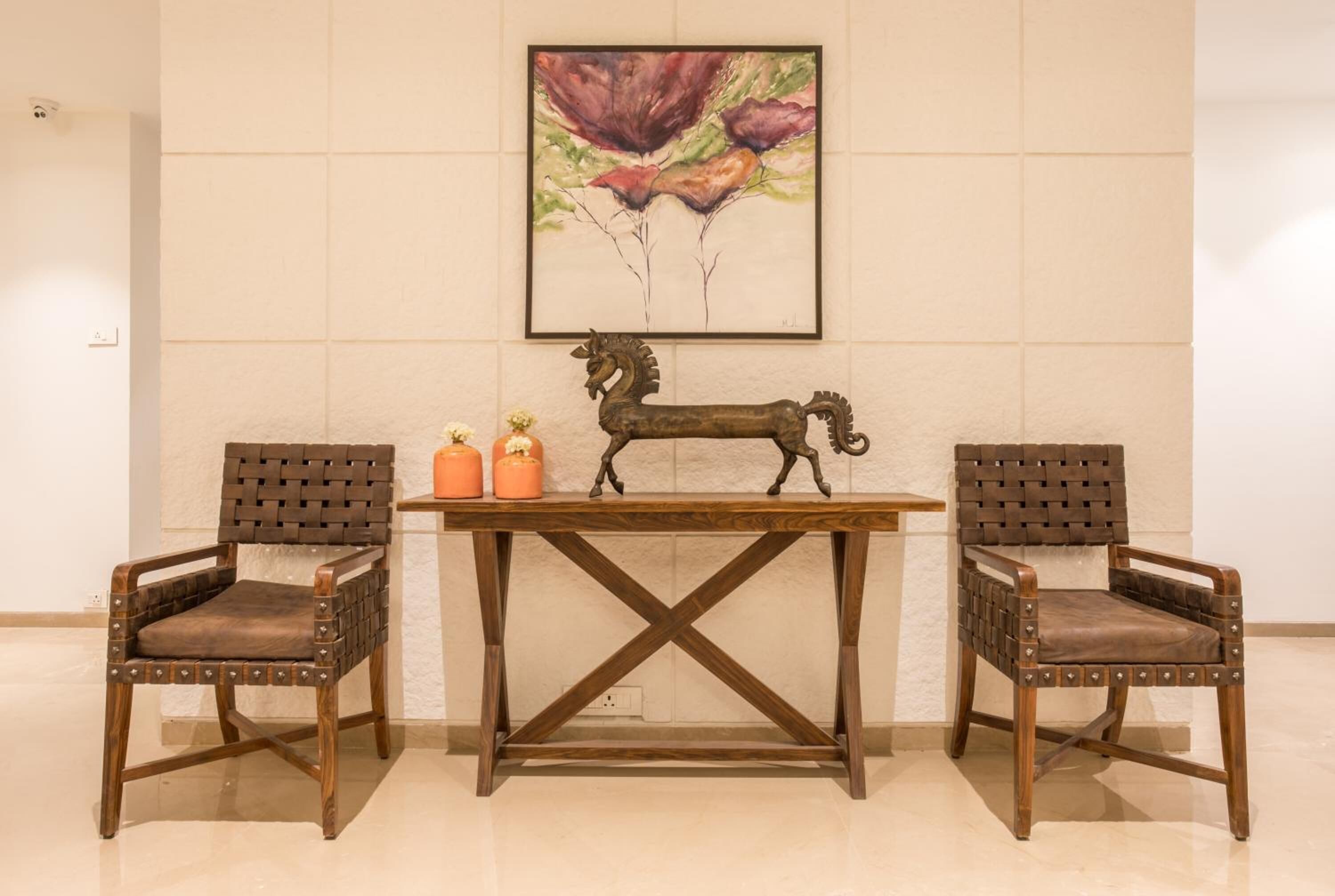 Uma mesa de madeira com uma escultura decorativa de cavalo, acompanhada por duas cadeiras de encosto trançado.