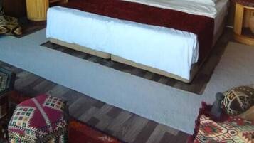 Uma cama com cabeceira, mesa de cabeceira, abajur e tapete estampado.