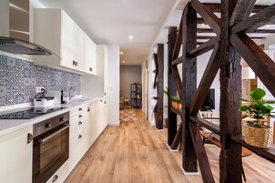 Cozinha com armários brancos, painel de azulejos e piso de madeira.