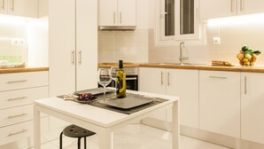 Uma cozinha moderna com armários brancos, bancada de madeira e uma mesa de jantar com um jogo americano.