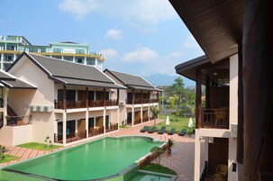 Um hotel com piscina, várias varandas e vista para montanhas.
