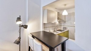 Uma cozinha compacta com armários brancos, bancada preta e luminária pendente.