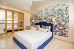 Quarto com uma cama grande, um mural floral na parede e um guarda-roupa com portas de correr.