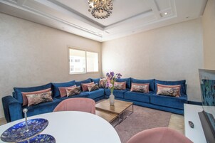 Uma sala de estar com um sofá modular azul, uma mesa de centro e um vaso com flores.