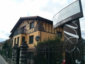 Um edifício amarelo com varanda e placa que diz "hotel restaurante".