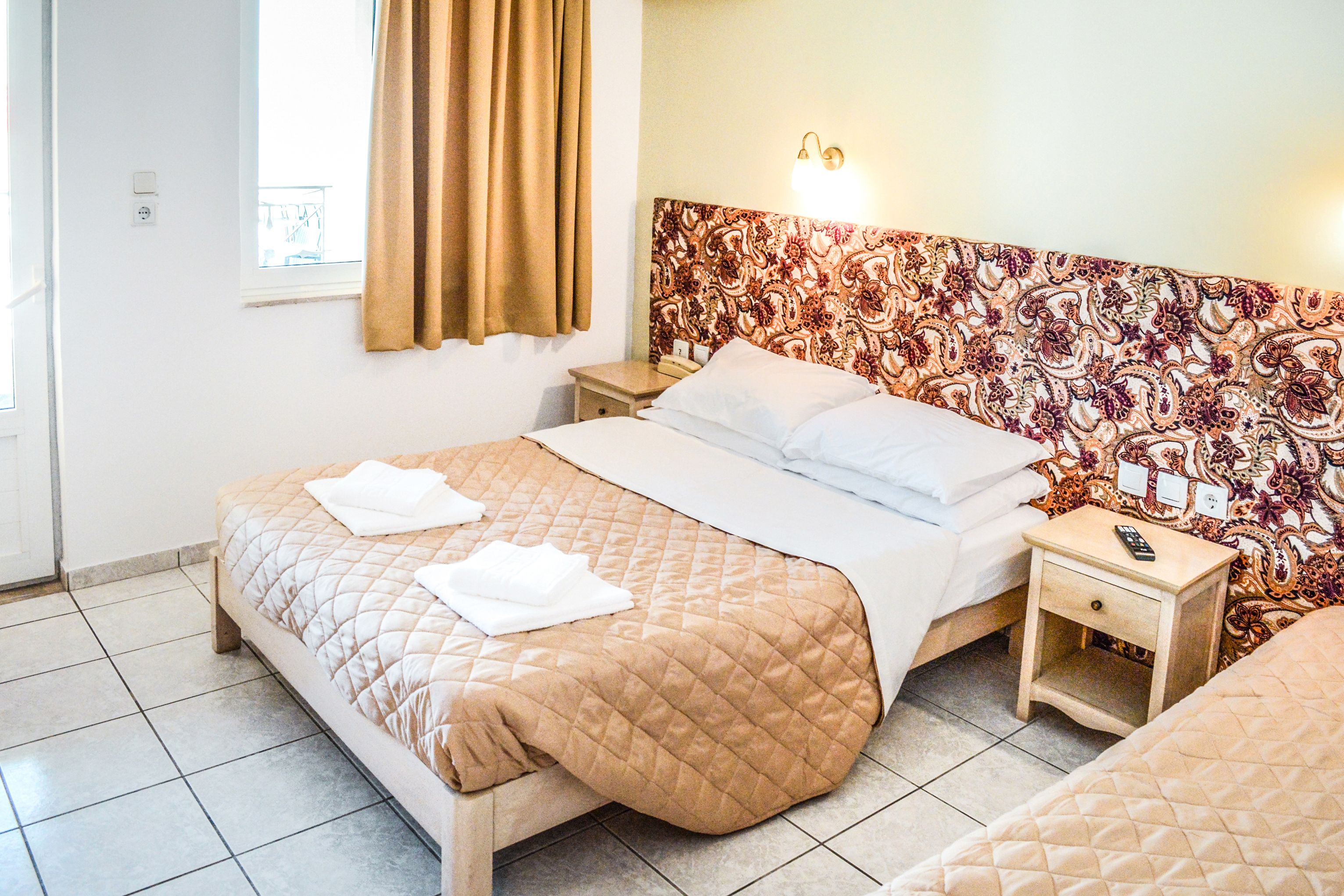 Quarto de hotel com uma cama, mesa de cabeceira e cabeceira estampada.