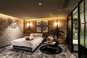 Quarto moderno com parede de tijolos, uma cama grande, uma escrivaninha e vista através de uma porta de correr.