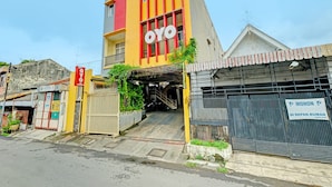 Um edifício de vários andares com uma placa chamativa 'OYO', uma entrada com portão e uma escadaria visível que leva à entrada.
