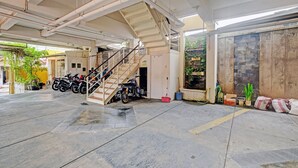 Área de estacionamento coberta com escadas, motocicletas e vasos de plantas.