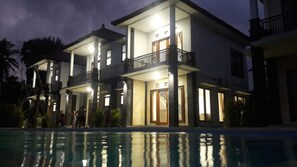 Edifício residencial com vários andares e piscina em primeiro plano.