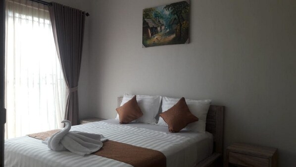Cama bem arrumada com manta branca e castanha, dois travesseiros e uma toalha em formato de cisne.