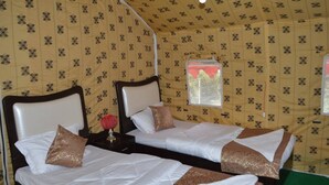 Quarto com tenda, duas camas, uma janela e uma mesa de cabeceira com abajur.